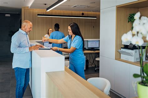 시니어 남성 환자가 리셉션 데스크에서 의료 양식을 작성하는 데 도움을 주는 아시아 간호사 25 29세에 대한 스톡 사진 및 기타 이미지 25 29세 30 34세 35