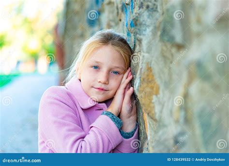 A Girl In A Pink Coat Stands Near The Wall Rubbing Close Ups Stock
