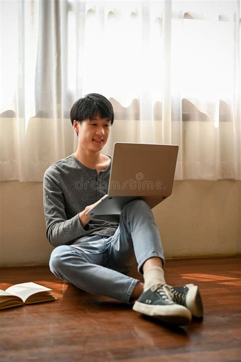 Portrait Of A Happy Young Asian Man Sits On The Floor In His Room