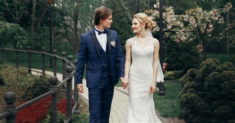 공원에서 휴식을 취하는 세련된 신랑 신부 행복한 럭셔리 웨딩 커플이 나무 사이를 걷고 웃고 있다 야외 리셉션에서 파란색 정장을 입은 남자와 흰색 드레스를 입은 여자 사진