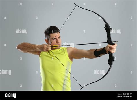 Man With Bow And Arrow Practicing Archery On Light Grey Background Stock Photo Alamy