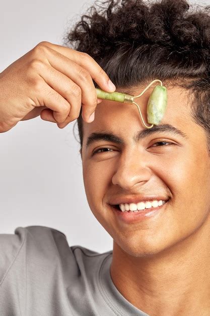 Premium Photo Young Handsome Smiling Guy Using Jade Depuffing Face