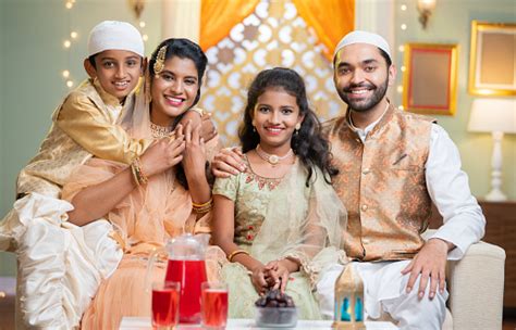 라마단 축제 기간 동안 집에서 소파에 앉아 카메라를 보면서 전통 의상을 입은 아이들과 함께 행복한 미소를 짓고 있는 인도 무슬림 커플 선물 관계 및 유대감의 개념 30 39