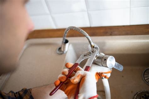 Close Up Of Plumber S Hands With Pliers Repairing Sink In Kitchen Stock