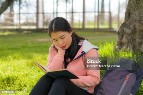 풀에 소설을 즐기는 젊은 아시아 여성 젊은 행복하고 예쁜 한국 소녀의 라이프 스타일 초상화는 독서와 공부 개념에서 아름다운 도시