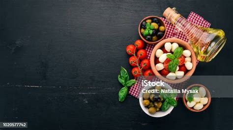 이탈리아 Caprese 샐러드 재료입니다 모 짜 렐 라 치즈 체리 토마토 바 질 잎 올리브 오일 후추 에 검은 나무 배경