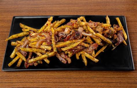 Fried French Fries With Pork Meat On Black Plate On Wooden Table Stock