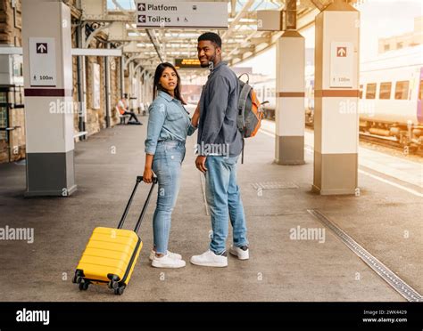 Cheerful Couple At Railway Station Waiting For The Train On Platform
