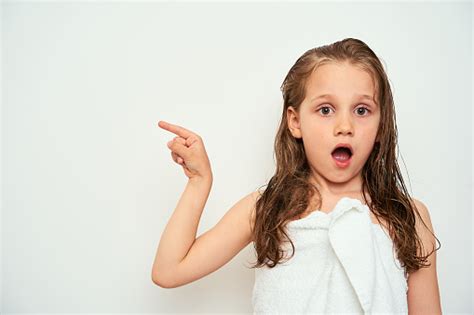 젖은 머리를 가진 작은 유치원 소녀는 흰색 배경에 싸여 얼굴 표정 데 손가락으로 흰색 수건을 가리키는 사진 Contingency Plan에 대한 스톡 사진 및 기타 이미지