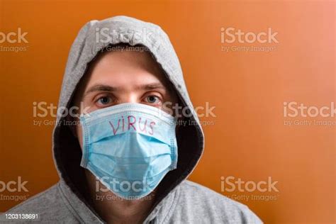 갈색 배경에 바이러스 단어가있는 의료 용 마스크를 쓰고 머리에 후드를 입은 남자의 초상화 코로나 바이러스 개념 호흡 보호 개념