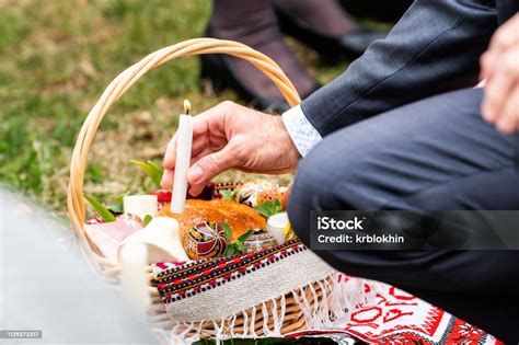 우크라이나 정교회 부활절 축복 고리 버들 세공 밀 짚 바구니에 캔 들을 배치 하는 수석 남자 손으로 잔디 화 염으로 교회 밖에