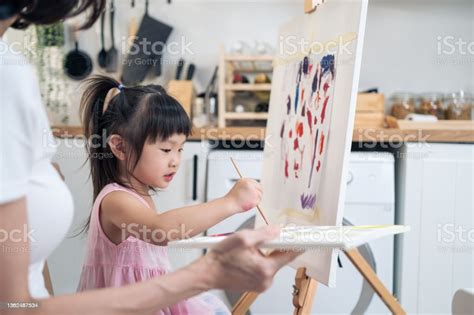 아시아 의 젊은 행복한 아이 딸 어머니와 함께 그림 보드에 착색 행복한 가족 활동 어린 소녀 아이는 수채화 페인트와 브러시와 함께 예술 사진을 그리는 방법을 배우고 엄마와