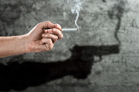 남성 손 들고 담배 총으로 벽에 그림자 근접 빛 배경 크리에이 티브 배경입니다 흡연의 개념 살인 Nekatin은 독 니코틴 중독