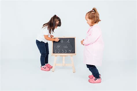 두 여자 검은 머리와 금발 머리와 다른 하나 클래스에서 분필 보드 옆에 스니핑 및 재생 2명에 대한 스톡 사진 및 기타 이미지