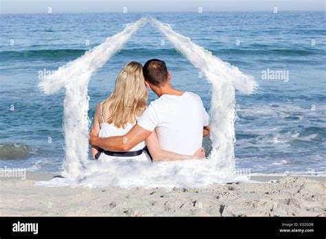 Composite Image Of Affectionate Couple Sitting On The Sand At The Beach