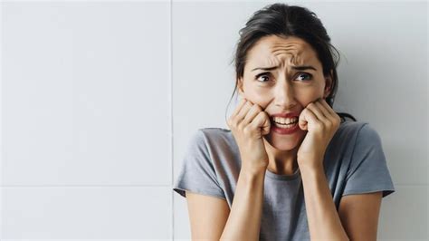 Woman Bites Finger Nails Looks Anxious At Camera Feels Worried About Something Being In Panic