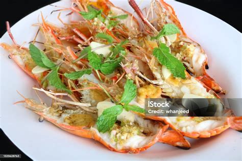 해산물 소스를 곁들인 신선한 강 새우를 가까이서 검은 색 배경에 흰색 접시에 마늘과 민트 잎을 얹은 사이드 뷰는 태국의 유명한 음식이 맛있습니다 갑각류에 대한 스톡 사진 및