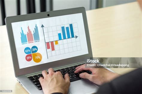 정장을 입은 사업가의 뒷모습은 사무실의 책상에 앉아 노트북 컴퓨터 키보드로 타이핑하고 그래프와 여러 가지 색상의 차트로 프리젠 테이션을합니다 개념에 대한 스톡 사진 및 기타