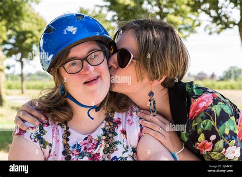 Portrait Of A Young White Woman Kissing A Woman With Down Syndrome