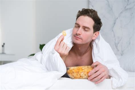 Premium Photo Young Man Eating Chips In Bed Bedroom Fast Junk Food