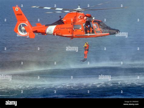 A Us Coast Guard Rescue Swimmer Is Lowered Into The Water During