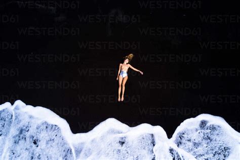 Aerial View Of Relaxed Female In Blue Shiny Swimsuit Bottom Lying Topless With Arm Stretched Out