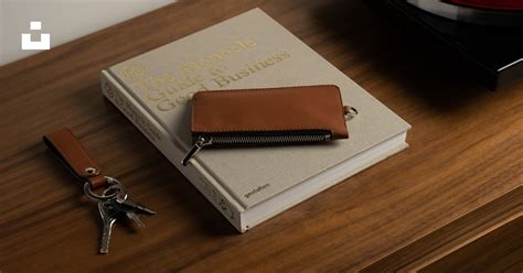 한 쌍의 열쇠 옆에 책 위에 앉아있는 갈색 지갑 사진 Unsplash의 무료 지갑 이미지