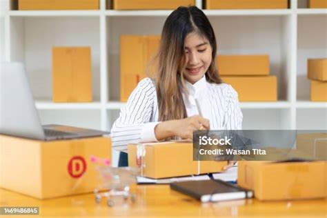 홈 오피스에서 일하는 작은 스타트업 비즈니스 여성의 여성이 노트북과 스마트폰으로 배송을 준비하기 위해 인터넷에서 주문을 확인합니다 20 24세에 대한 스톡 사진 및 기타