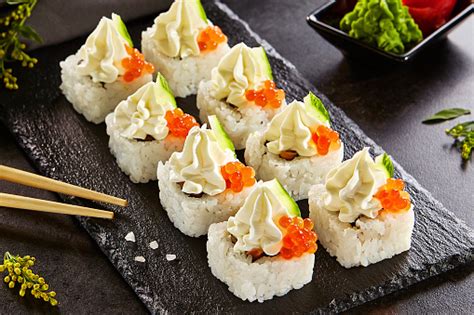 블랙 슬레이트 플레이트에 세계 각국의 마키 스시 롤 나무 젓가락 녹색 와사비 절인 생강과 함께 제공됩니다 다크 스톤 배경에 마키 스시 롤 일본 세트 0명에 대한 스톡 사진