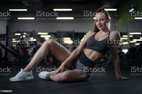 Fitness Girl Posing In The Gym Sitting On The Floor Showing Off Her
