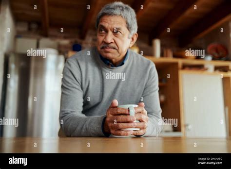 Pensive Retired Biracial Elderly Male Leaning On Modern Kitchen Counter