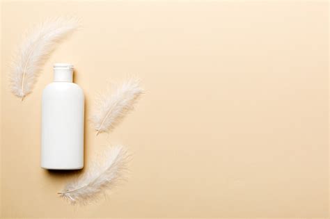 타조 깃털이있는 분홍색 파스텔 배경에 스킨 케어 세럼 세트 스파 화장품 크림 항아리 브랜딩 모형 복사 공간이있는 상판 받침대에