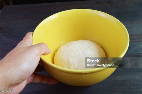 반죽한 반죽 한 그릇을 테이블 위에 올려 놓은 남자의 손이 굽기 전에 부풀어 오르도록 합니다 갈색에 대한 스톡 사진 및 기타
