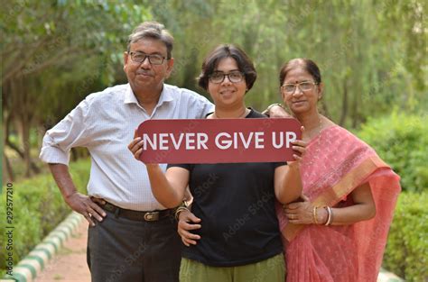 Senior Bengali Indian Couple With Her Young Daughter Holding A Placard