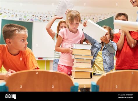 Classmates Stacking Books On Bench During Activity In Classroom Stock