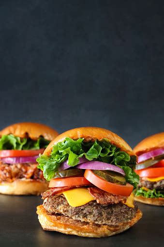 빵 빵 치즈 버거 닭고기 베이컨 치즈 버거 고기 패티 베이컨 러셔 녹는 가공 치즈 조각 양상추 잎 얇게 썬 토마토 피클과 붉은 양파 조각 검은 배경 복사 공간에 세 개의