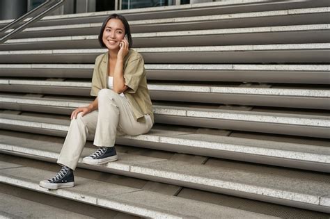 Une Fille Asiatique Souriante Est Assise Dans Les Escaliers Du Bâtiment
