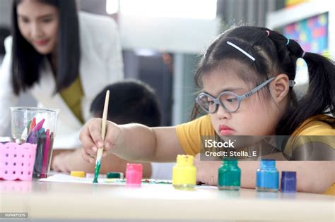 행복한 아이들은 학교에서 공부하는 동안 친구들과 즐거운 시간을 보내고 다운 증후군을 앓고있는 소녀는 미술 교실에서 종이에 집중