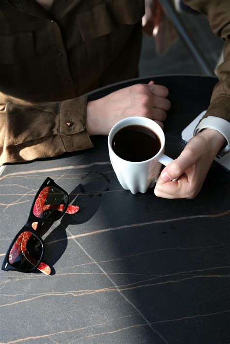 그림자 기분 좋은 깨지다 나무 테이블 대조 따뜻함 라이프스타일 머그 미니멀리즘 반사 블랙 커피 선글라스 손 수직 쐈어 술을 마시다 실내 실루엣