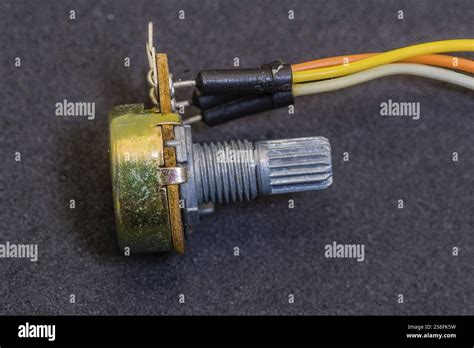 A Metal Potentiometer With Wires Attached Lying On A Dark Background