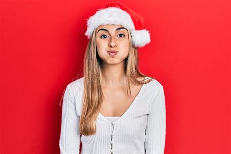 Beautiful Hispanic Woman Wearing Christmas Hat Puffing Cheeks With