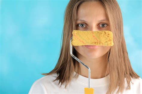 파란 배경에 고립 된 벽화에 페인트 롤러를 들고 캐주얼 옷을 입고 젊은 미소 아름다운 여자 악기 액세서리 리노베이션 아파트 룸을위한 도구 수리 홈 컨셉 25 29세에 대한