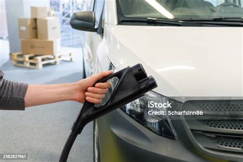 남성의 손이 차고에 있는 전기 밴의 배경에 전기 충전기의 충전 플러그를 잡고 있습니다 개념 교통수단에 대한 스톡 사진 및 기타 이미지 Istock