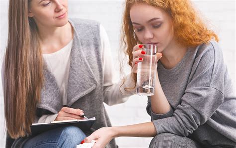 여성 환자를 위로하는 심리 치료사 진정하기 위해 물 한 잔을 주는 Alcoholics Anonymous에 대한 스톡 사진 및