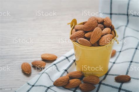 복사 공간이있는 부엌 테이블 배경에 스카치 패턴 테이블 천 위의 노란색 양동이에 아몬드 0명에 대한 스톡 사진 및 기타 이미지