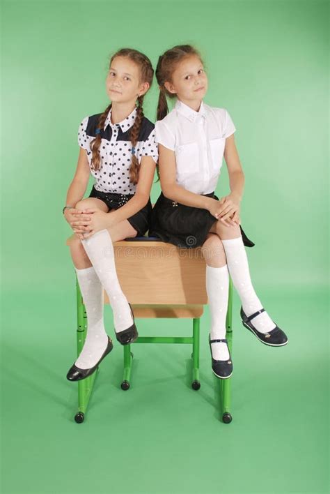 Deux Filles Dans Un Uniforme Scolaire Se Reposant Sur Le Bureau Photo