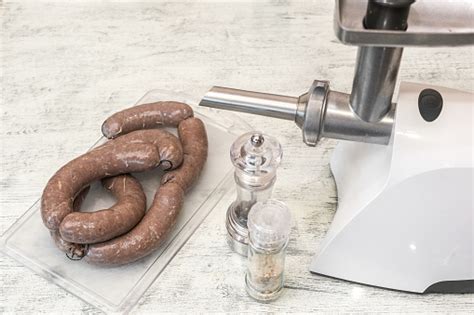 생 집에서 만든 소시지 스레드로 단단히 뽑아 플라스틱 도마에 누워 다진 고기와 향신료를 요리하기위한 고기 분쇄기 요리에 Piquancy를 추가합니다 방부제가 없는 건강한