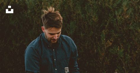 녹색과 검은색 체크무늬 드레스 셔츠와 회색 데님 청바지를 입은 남자가 검은색 Dslr 카메라를 들고 있다 사진