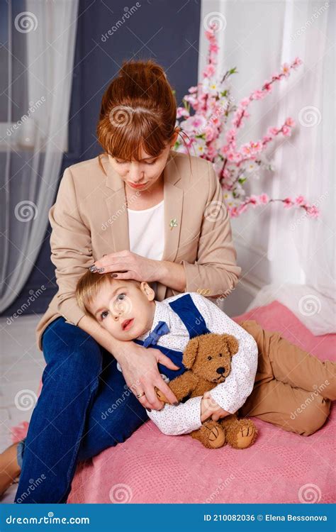 Забота о матери для ребенка Молодая мать охватывает ее маленького сына в кровати Стоковое Фото