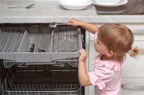 Menina Loira Adorável Que Ajuda Na Cozinha a Retirar Placas Da Máquina